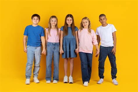 Friendly Group Of Preteen Pupils Holding Hands In Bright Yellow Studio