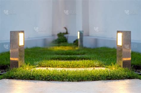 地面灯照明大理石人行道在晚上后院与绿色草坪，特写灯照明温暖光大理石路面。素材 花瓣网