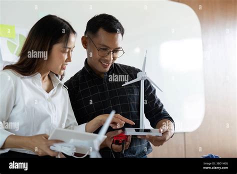 Sustainability And Engineering Engineers Collaborating On Wind Energy Models In A Modern Office