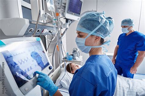 Hospital Nurses Checking On Woman Patient At Intensive Care Unit And