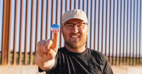 대통령 선거 상원의원 하원 의원 또는 지방 선거에 나는 투표했습니다 스티커를 가진 젊은 백인 남성 그는 봄날에 미국과 멕시코를 가르는 미국 국경 장벽 울타리에 서