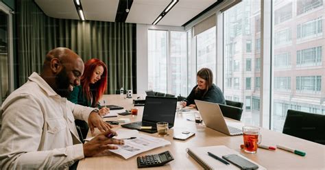 테이블 주위에 앉아 노트북으로 작업하는 한 무리의 사람들 사진 Unsplash의 작업 이미지