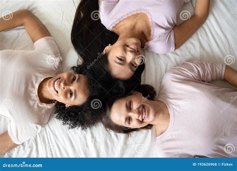 Three Diverse Best Girlfriends Smiling Lying In Bed Top View Stock