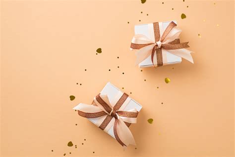 생 발렌타인 데이 장식 의 상단 보기 사진 빛나는 갈색과 밝은 베이지 색 리본 리본 은 카피 스페이스와 고립 된 베이지 색 배경에 황금 하트 모양의 색종이 스팽글 활 흰색