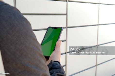 소포 사물함 옆에있는 녹색 스크린 크로마 키가있는 휴대 전화를 들고있는 여성 손 쇼핑 사물함에서 소포를 수집합니다 휴대 전화