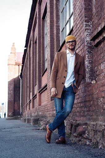 야외서 강모와 안경에 세련된 잘 생긴 젊은 남자의 초상화 남자는 재킷과 셔츠를 입고 벽에 기대어 개념에 대한 스톡 사진 및 기타