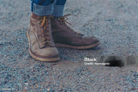 건설 현장에서 일하는 근로자를 위한 시공 부츠 안전 신발을 착용하는 남성 엔지니어는 정유 공장의 배경에 청바지 브라운 부츠 노동자를 착용합니다 엔지니어 안전 산업 패션 신발