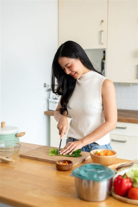An Attractive Happy Asian Woman Cutting Lettuces On A Cutting Board