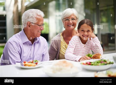 Lunch With Grandpa And Granny A Granddaughter Sitting With Her Grandparents While Enjoying A