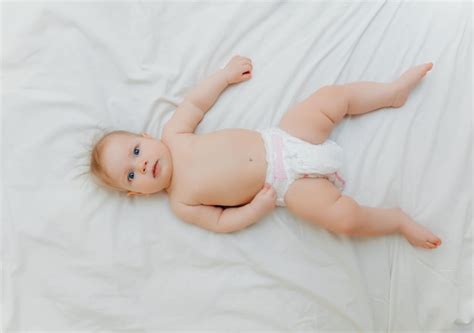 Premium Photo A Happy Joyful Baby In Diapers Is Lying On A White Bed