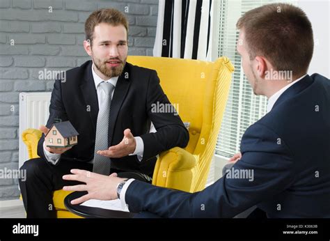 Real Estate Agent Discussing With Customer Blueprints And House Model