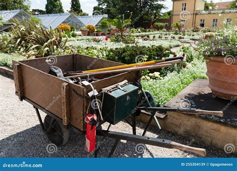 A Gardener Wheelbarrow With The Gardening Tools In The Gardens With
