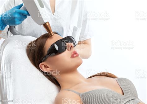 그녀의 얼굴에 탄소 마스크를 가진 여자 미용사는 젊은 아름다운 소녀의 피부의 문제 영역에 레이저 탄소 박리를 않습니다 화장품 및 전문 스킨 케어 25 29세에 대한 스톡