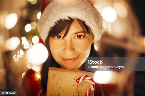 즐거운 성탄절 산타 모자와 빨간 스웨터 크리스마스 트리 조명 축제 방 저녁에 불빛에 선물을 들고 있는 소녀 현대 공예 선물 여 대기 순간 가족에 대한 스톡 사진 및 기타