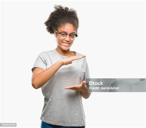 젊은 아프리카 미국 여자 손으로 크고 큰 크기 표시 측정 기호를 보여주는 몸짓 격리 된 배경 위에 안경 착용 카메라를 보고 웃 고 측정 개념입니다 개념에 대한 스톡 사진 및