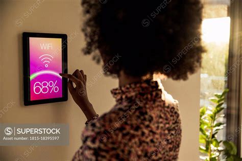 Woman Using Home Automation Device On Wall Superstock