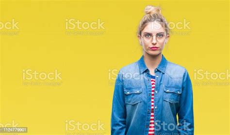 젊은 아름 다운 금발 여자 얼굴에 심각한 표정으로 고립 된 배경 위에 안경을 착용 카메라를 보고 간단 하 고 자연 스러운 금발 머리에 대한 스톡 사진 및 기타 이미지