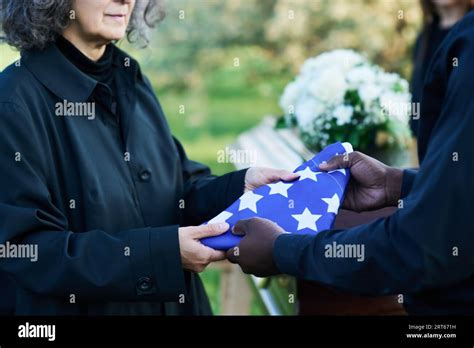 Mature Grieving Widow In Black Attire Taking Folded Stars And Stripes Flag From Hands Of African