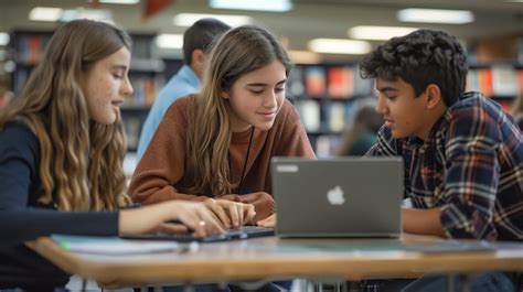 Three Teenagers Two Girls And One Boy Are Looking At A Laptop In A