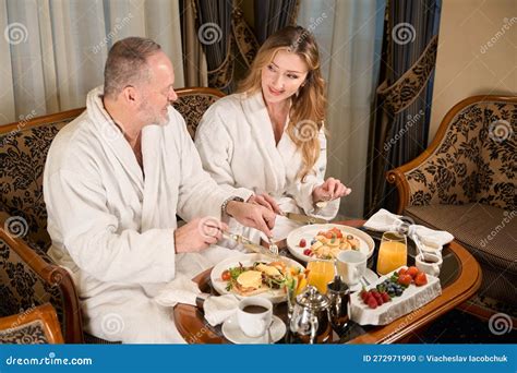 Married Couple In Bathrobes Having Breakfast In Luxury Hotel Room Stock