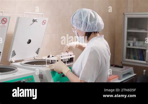 An Adult Female Doctor In A White Lab Coat And Hygienic Gloves Places Blood Tests Stored In Test