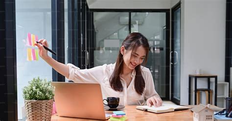 웃고 있는 여성 직원이 노트북 컴퓨터로 작업하고 사무실의 유리 벽에 스티커 메모를 하고 있다 사진 Unsplash의 태국 이미지