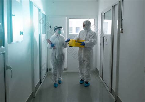 两名身穿防护服的生物学家在实验室走廊携带图片 包图网企业站