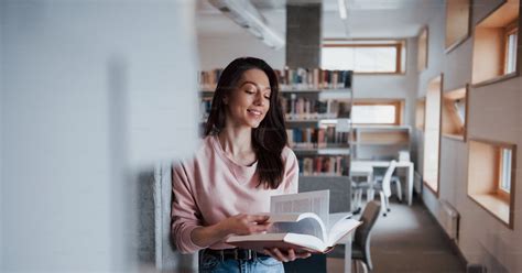 지적 성장 캐주얼 옷을 입은 갈색 머리 소녀는 책으로 가득한 도서관에서 즐거운 시간을 보내고 있습니다 사진 Unsplash의 도서관 이미지