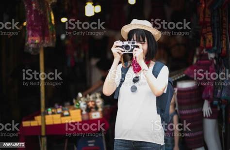 Hipster 아름 다운 젊은 여자는 필름 카메라와 배낭 태국 방콕 시티의 시내 거리에 산책에 재미 스타일 Hipster 스타일 개념 여행 촬영 거리에 대한 스톡 사진 및