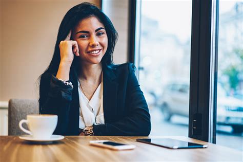 아름 다운 긍정적인 Hipster 여자의 반 길이 초상화 커피와 현대 장치 실내에서 재현 하는 세련 된 옷을 입은 쾌활 한 여자 사람이 카페에서 휴식 하는 동안 카메라를