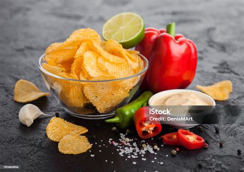 검은 돌 테이블 배경에 파프리카와 고추 고추와 감자 감자칩 칩 유리 그릇 접시 라임과 매운 소스를 곁들인 붉은 파프리카 후추 0