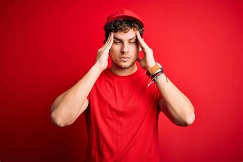 두통이 절실하고 통증과 편두통 때문에 스트레스로 고통 고립 된 빨간 배경 위에 서 곱슬 머리를 가진 젊은 금발 배달 남자 머리에 손을 걱정하는에 대한 스톡 사진 및 기타