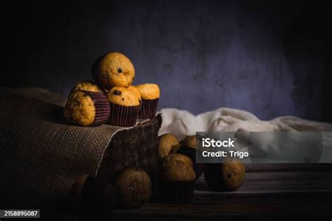 흰 천을 뒤로하고 나무 통나무에 사이드 라이트가 있는 미니 초콜릿 칩 컵케이크 어두운 배경 복사를 위한 공간의 수직 정물 사진