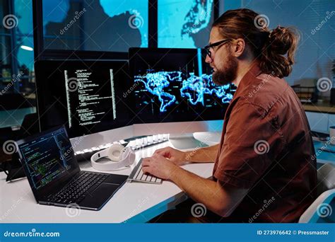 Young Serious Male Programmer Looking At Coded Data On Computer Screen