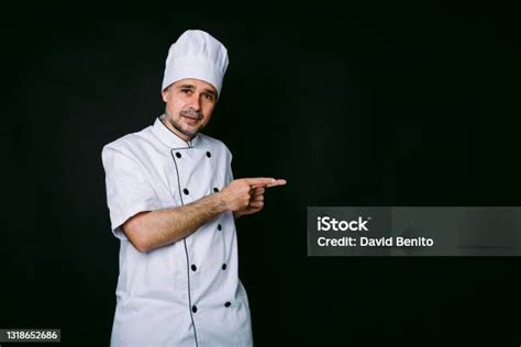 검은 색 배경에 검은 배경을 가리키는 재킷과 주방 모자를 착용한 요리사 요리사 40 44세에 대한 스톡 사진 및 기타 이미지 40 44세 가리키기 개념 Istock