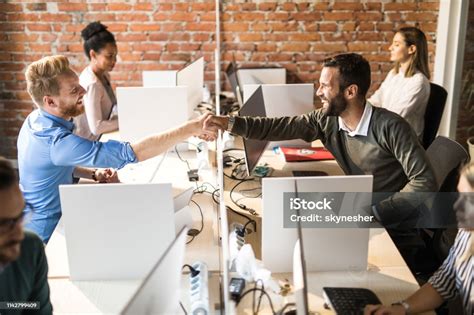 Happy Male Programmers Shaking Hands While Working At Corporate Office