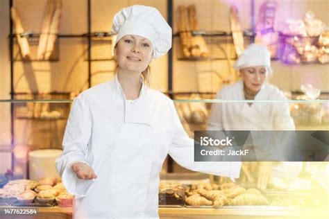 흰 코트와 요리사 모자를 쓴 여성 제빵사가 신선한 빵과 빵을 사도록 초대합니다 35 39세에 대한 스톡 사진 및 기타 이미지 35 39세 65 69세 Croatian