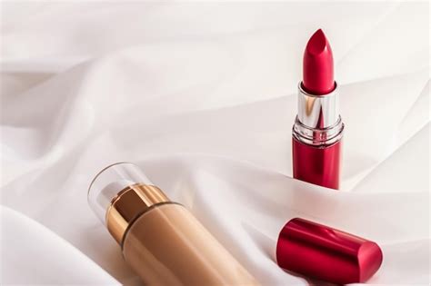 베이지 색조 크림 병 메이크업 플루이드 파운데이션 베이스와 실크 배경 화장품에 빨간 립스틱을 고급 뷰티 브랜드 홀리데이 디자인으로 프리미엄 사진
