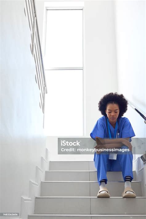 스트레스를 받는 여성 의사나 간호사가 수술복을 입고 병원 계단에 앉아 있다 간호사에 대한 스톡 사진 및 기타 이미지 간호사 정신적 스트레스 정서적 탈진 Istock