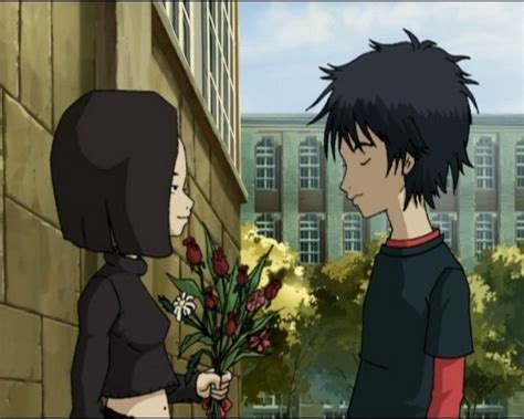 A Man And Woman Standing Next To Each Other In Front Of A Building With Flowers