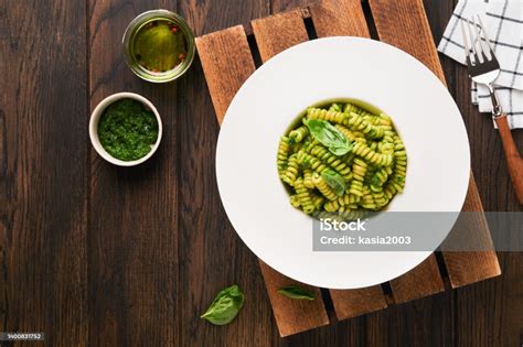 페스토와 이탈리아 푸실리 파스타 바질 페스토와 허브 파르 메산 치즈 바질 및 마늘을 오래된 나무 테이블 배경에 흰색 접시에 곁들인 Fusilli 파스타 상단 보기 공간을