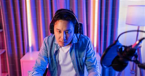 아시아의 매력적인 Esport 남성 게이머는 컴퓨터에서 온라인 비디오 게임을합니다 잘 생긴 남자 게임 플레이어는 행복하고 흥분을 느끼고 집에서 사이버 토너먼트를하는 동안