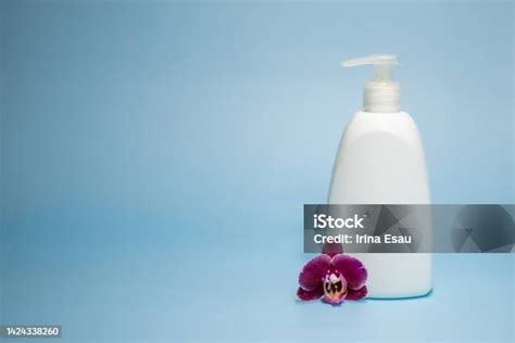 펌프 디스펜서 펌프와 Blau 배경에 난초 꽃이있는 흰색 화장품 플라스틱 병 젤 로션 크림 샴푸 목욕 거품을 위한 액체 콘테이너