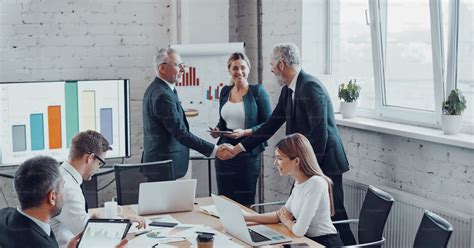 자신감 있는 사업가들이 회의실에서 동료들과 함께 일하면서 악수하고 웃고 있다 사진 Unsplash의 실내 이미지