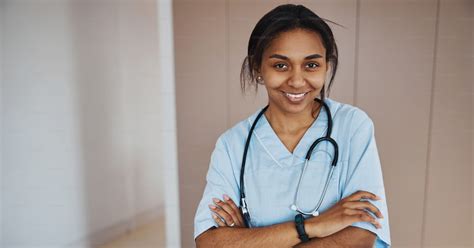 의료 유니폼을 입은 쾌활한 아프리카계 미국인 젊은 여성이 카메라를 보고 가슴 위로 팔짱을 끼면서 웃고 있다 사진 Unsplash의 간호사 이미지