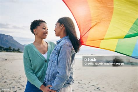 게이 깃발 레즈비언 커플은 여행 자유와 유대 보살핌과 자연 속에서 함께 행복하기 위해 해변에서 함께합니다 무지개 사랑 바다