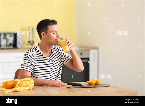 Handsome Man Drinking Fresh Orange Juice In Kitchen Stock Photo Alamy