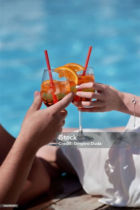 수영장 옆에서 여름 파티에 아페롤 스프리츠 칵테일과 함께 토스트를 곁들인 커플 복사 공간 이벤트 축하 컨셉 트라디티오안탈 이탈리아식페리티프 수영장 스포츠 경기장에 대한 스톡