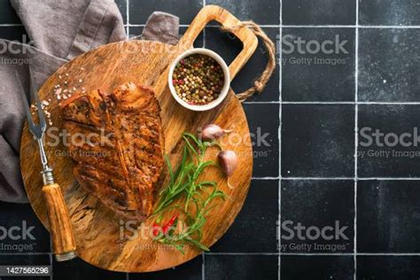 생 스테이크 Tbone 또는 포터 하우스 스테이크 Tbone 또는 포터 하우스는 콘크리트 배경에 오래된 나무 스탠드에 향신료 소금 및 로즈마리와 함께 소스에 담겨 있습니다