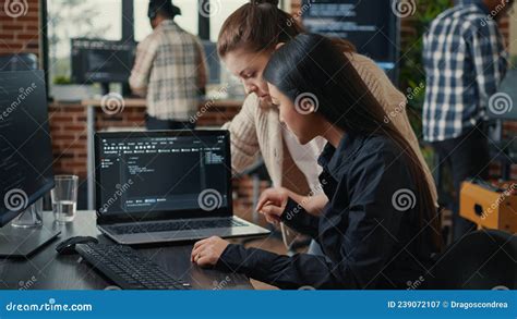 team of software developers talking about source code running on laptop